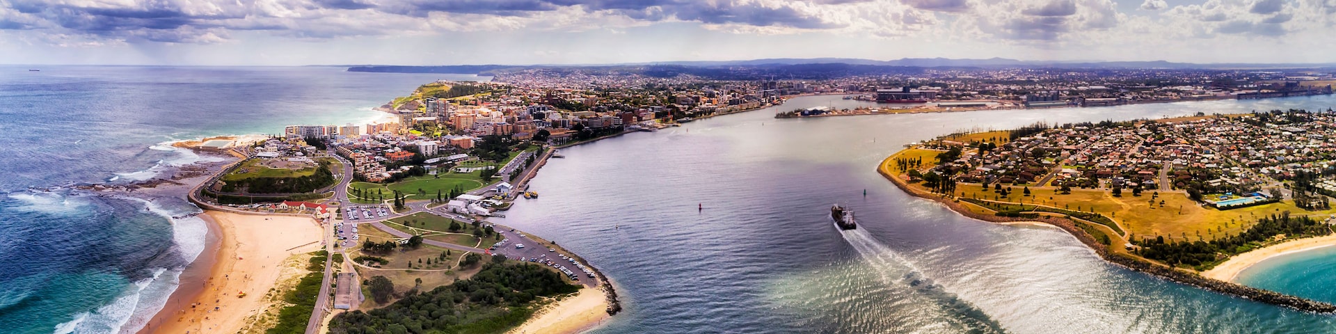 Uma cidade costeira com praia, rio e área urbana densa.