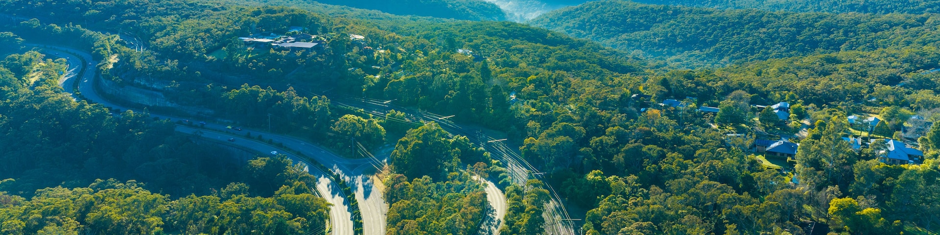 Um rio serpenteando por um vale com casas dispersas e uma ponte.