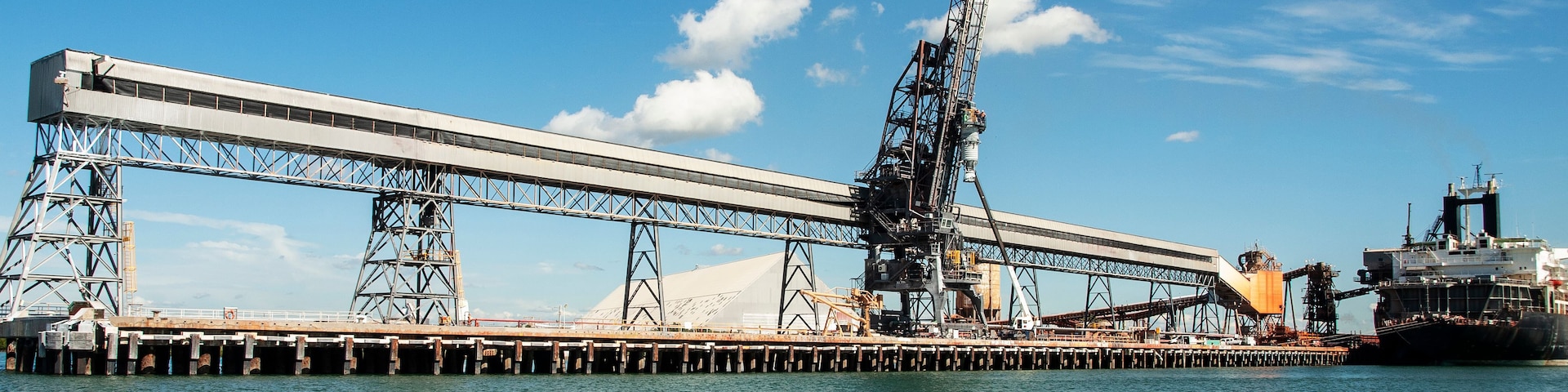 Um grande cais industrial com guindastes e um navio atracado.