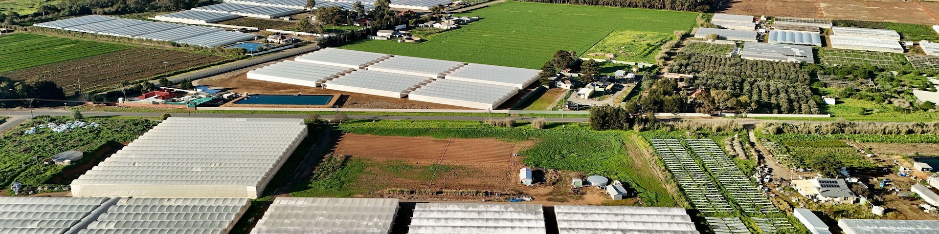 Uma grande instalação agrícola com várias estufas e campos.