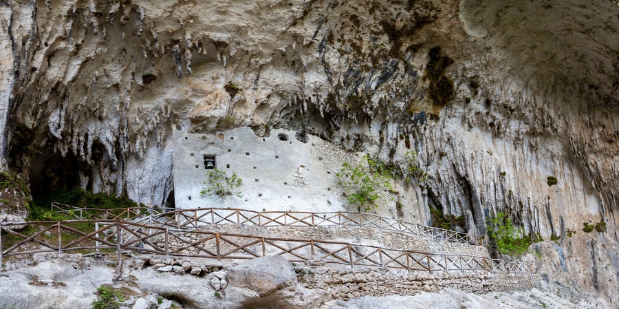 Entrada de uma caverna com cerca de madeira e uma pequena janela.