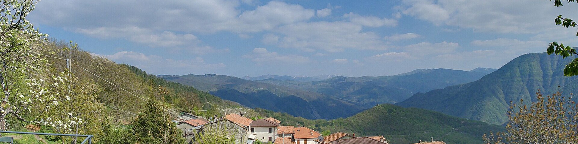 Uma aldeia aninhada num vale, com casas em socalcos e montanhas ao fundo.