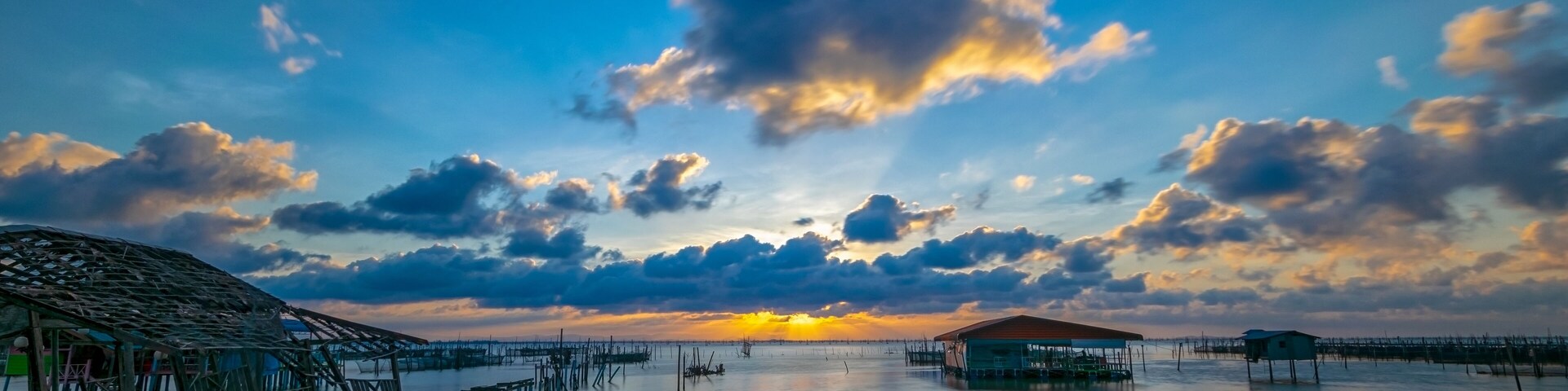 Um cais com um píer e um barco à vista, sob um céu ao pôr do sol.