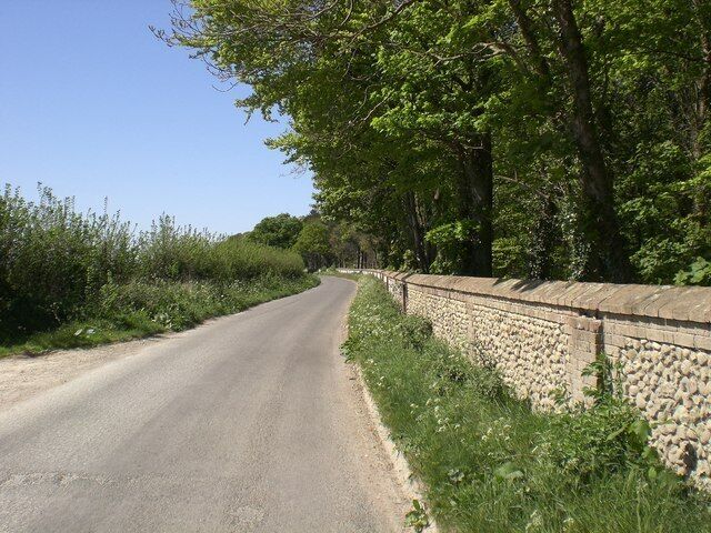 Uma estrada rural ladeada por muros de pedra e vegetação exuberante.