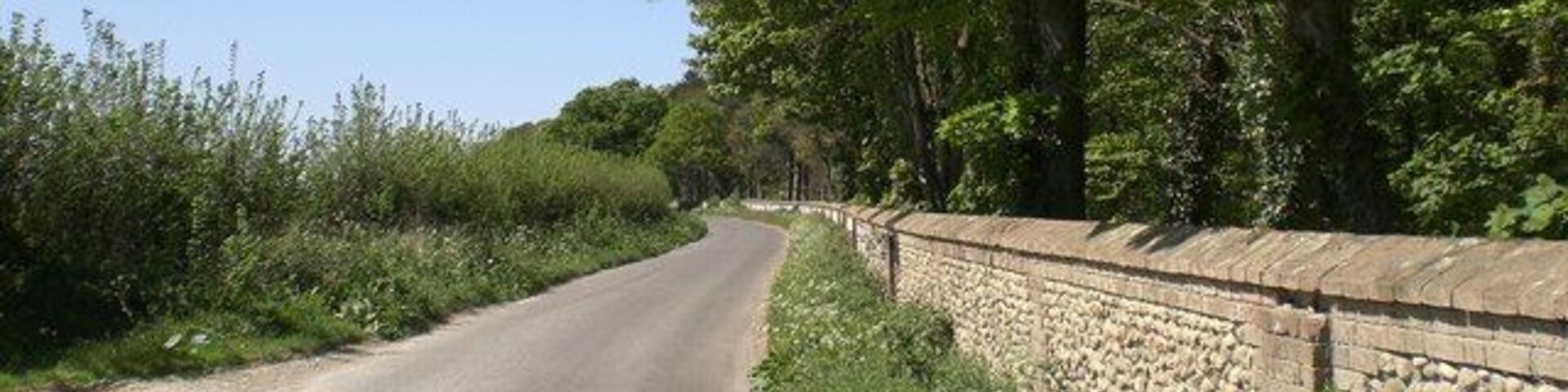 Uma estrada rural ladeada por muros de pedra e vegetação exuberante.