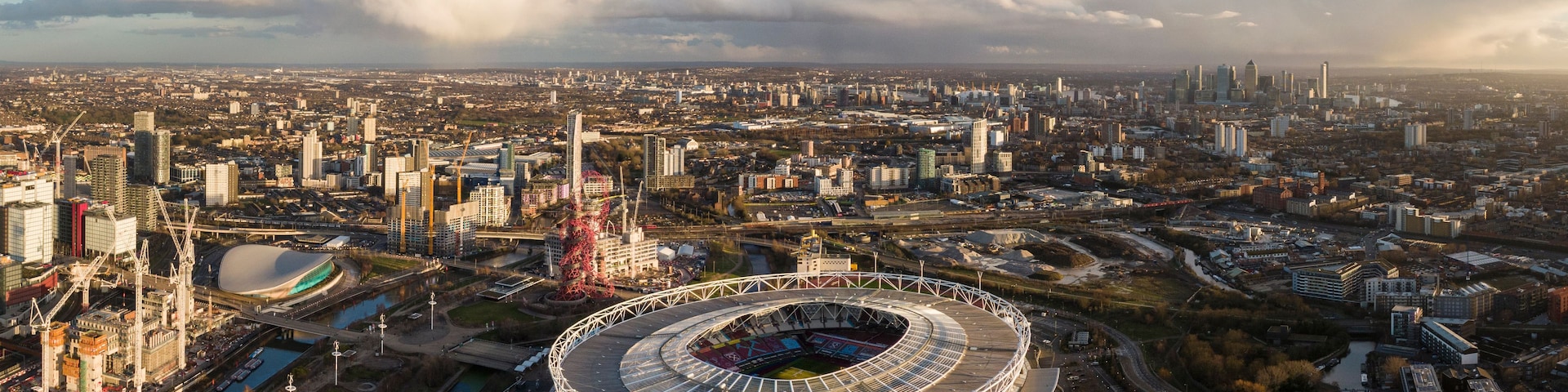 Um estádio grande rodeado por um horizonte urbano com diversos edifícios e um rio.