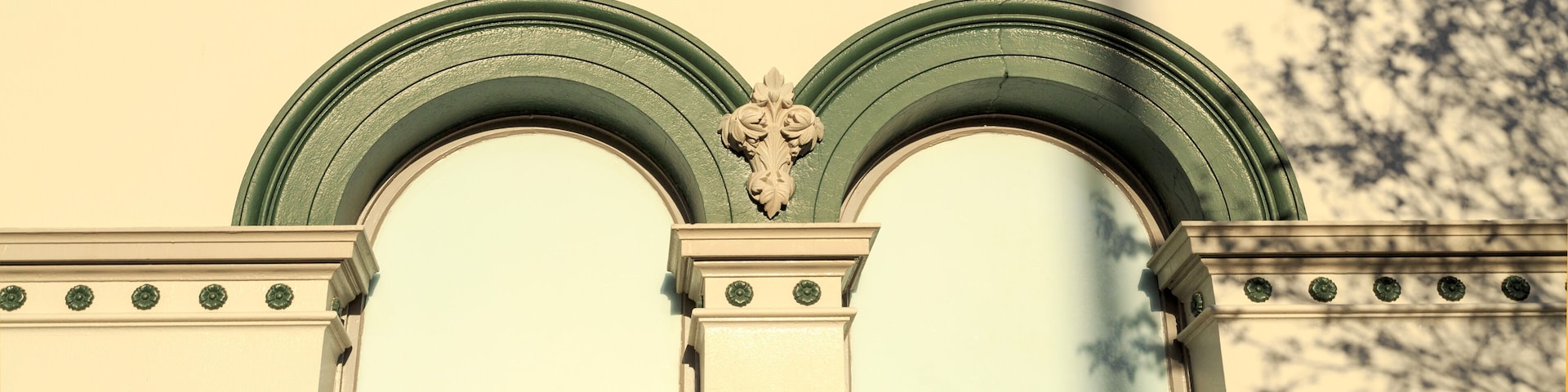 Um edifício com duas janelas em arco e um detalhe decorativo acima.