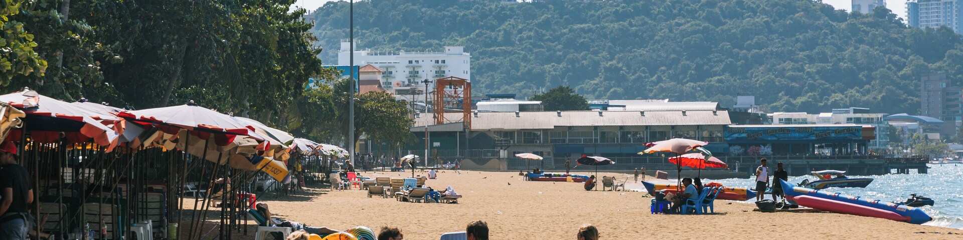 Uma praia com guarda-sóis, cadeiras de praia e pessoas relaxando.