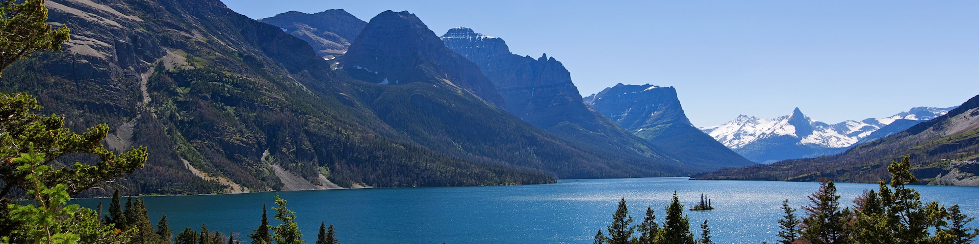Um lago de montanha rodeado por montanhas florestadas.