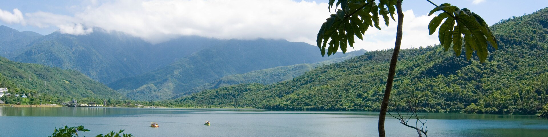 Um lago calmo rodeado por colinas verdes exuberantes e um céu claro.
