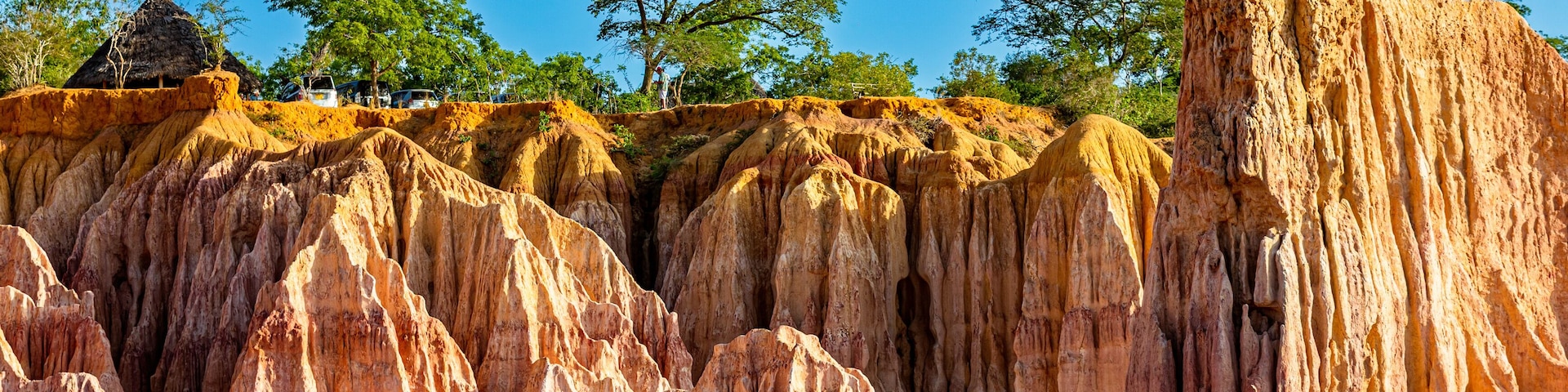 Paisagem acidentada com formações imponentes de arenito e uma pequena cabana.