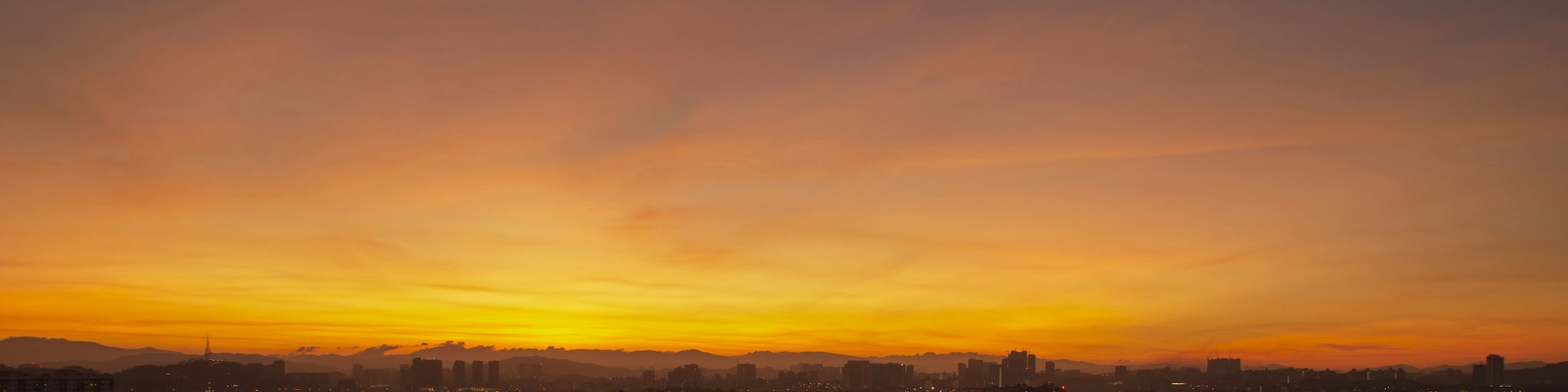 Silhueta de um horizonte urbano ao pôr do sol, com céu degradê.