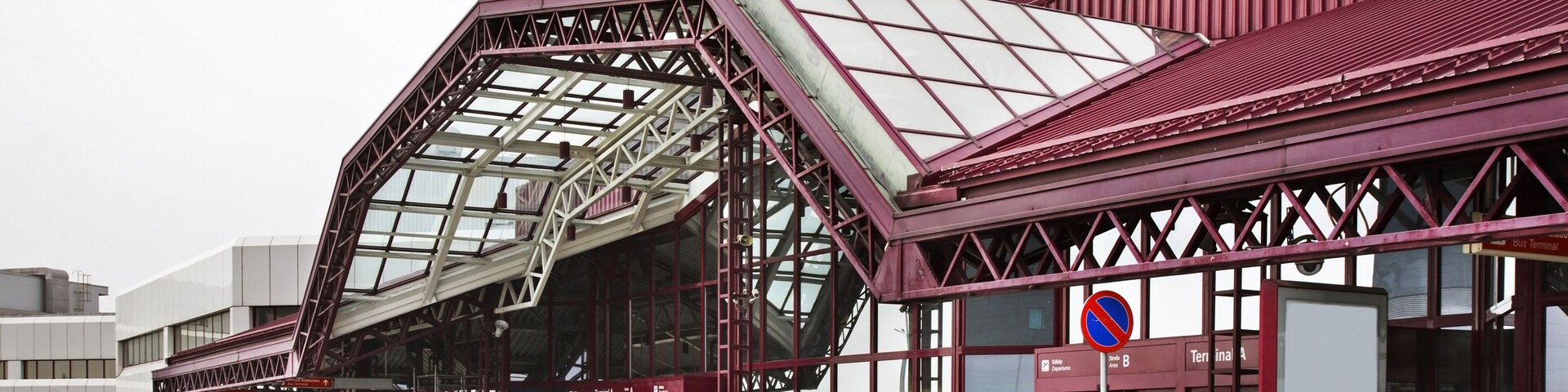 Um terminal rodoviário com uma estrutura de telhado metálica em vermelho e branco.