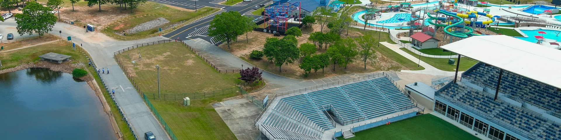 Vista aérea de um complexo esportivo com estádio, estacionamento e parque aquático.