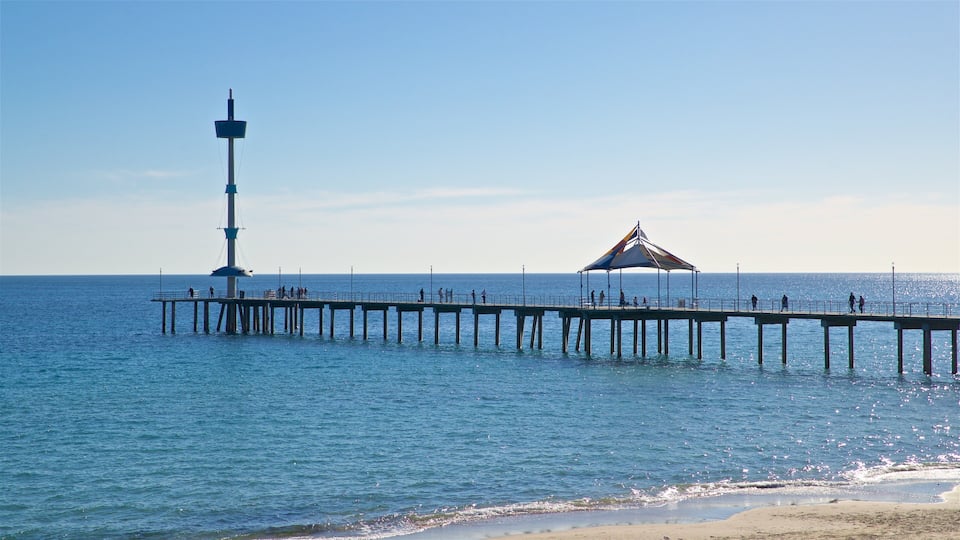 Um cais que se estende para o mar, com um farol e um pavilhão com sombra.