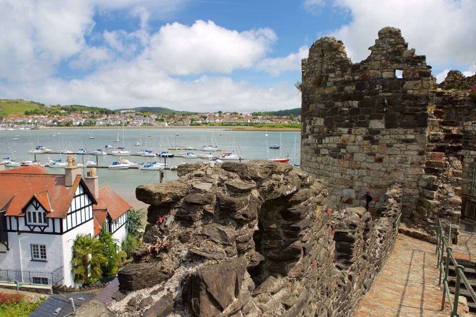 Uma torre de pedra histórica e ruínas perto de um porto com barcos.