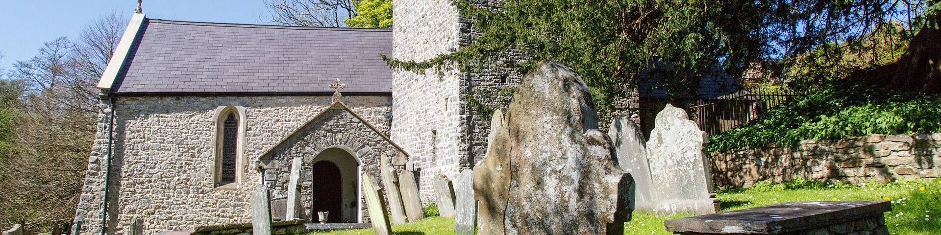 Uma igreja de pedra com um campanário e um cemitério com lápides.