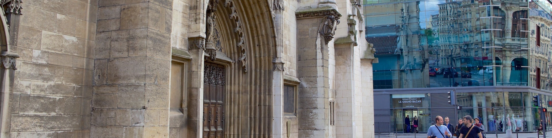Um edifício histórico de pedra com arcos ornamentados e uma estrutura moderna de vidro ao fundo.
