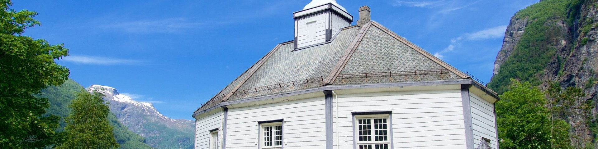 Geiranger featuring a cemetery and a church or cathedral as well as a small group of people
