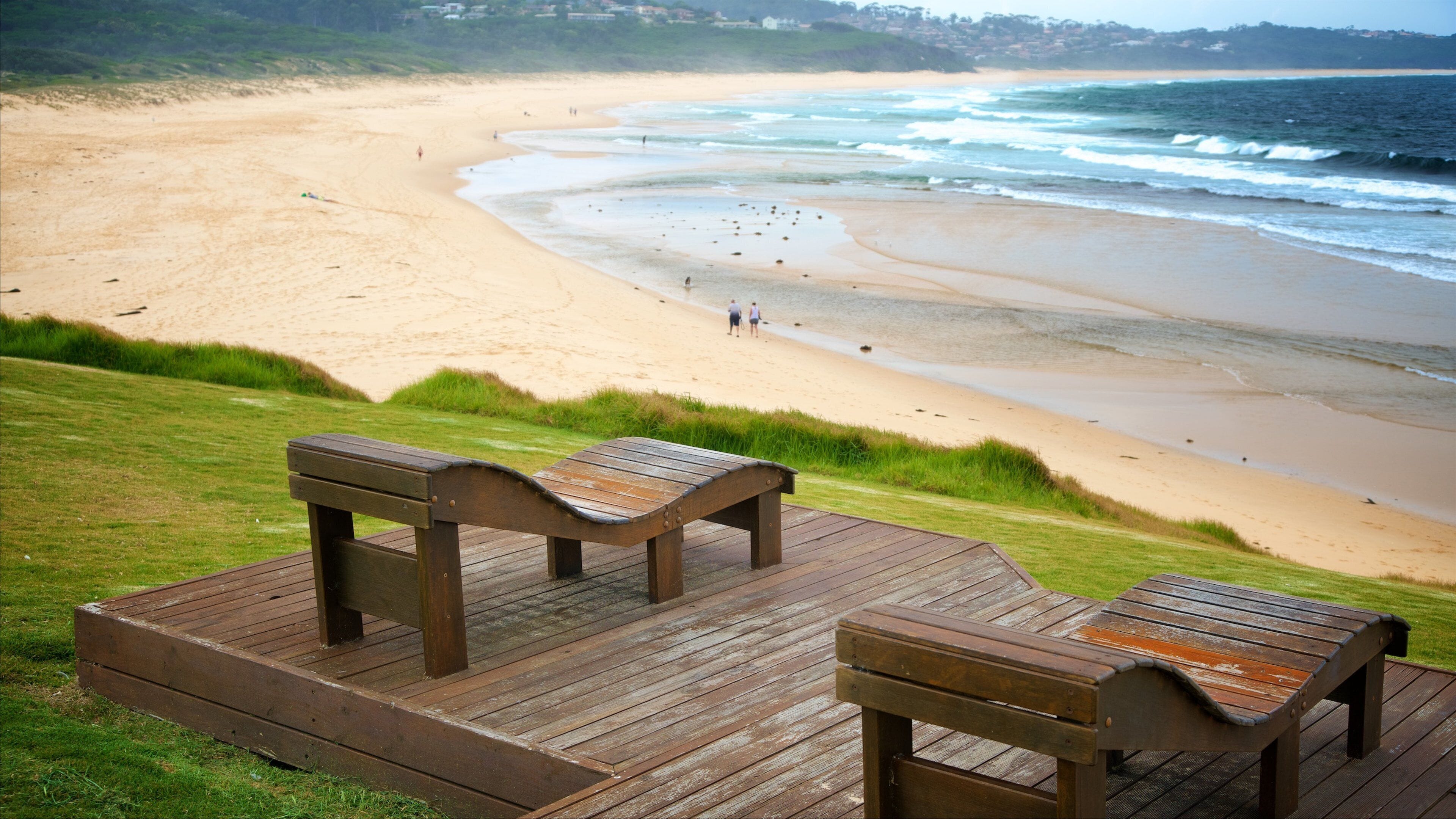 Uma praia com bancos de madeira com vista para o oceano.
