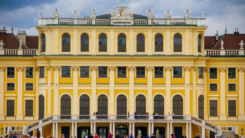 Um edifício grande e amarelo com janelas em arco e uma varanda central.