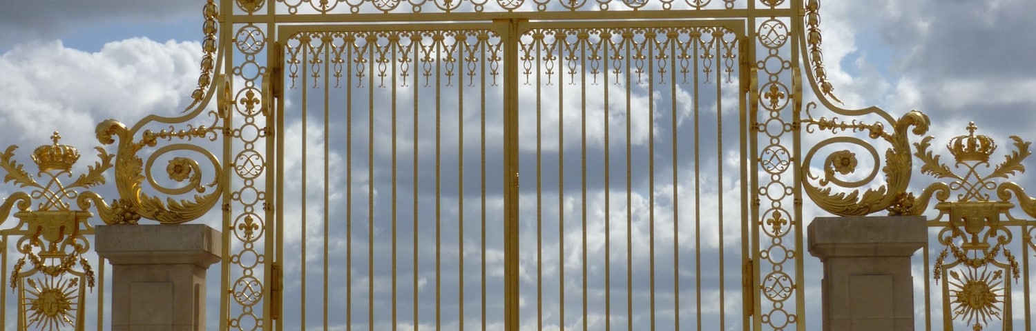 Um portão dourado e ornamentado com desenhos detalhados e um emblema central.