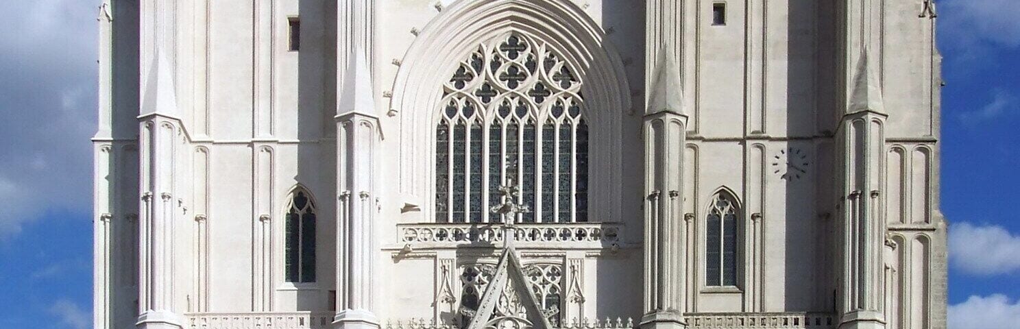 Uma grande catedral gótica com arcos ogivais, esculturas intrincadas em pedra e altas torres.