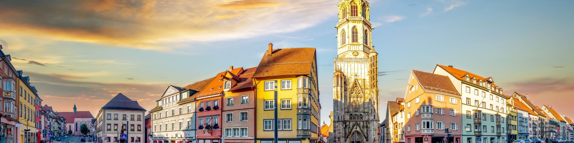 Uma rua com edifícios coloridos e uma torre de igreja imponente.