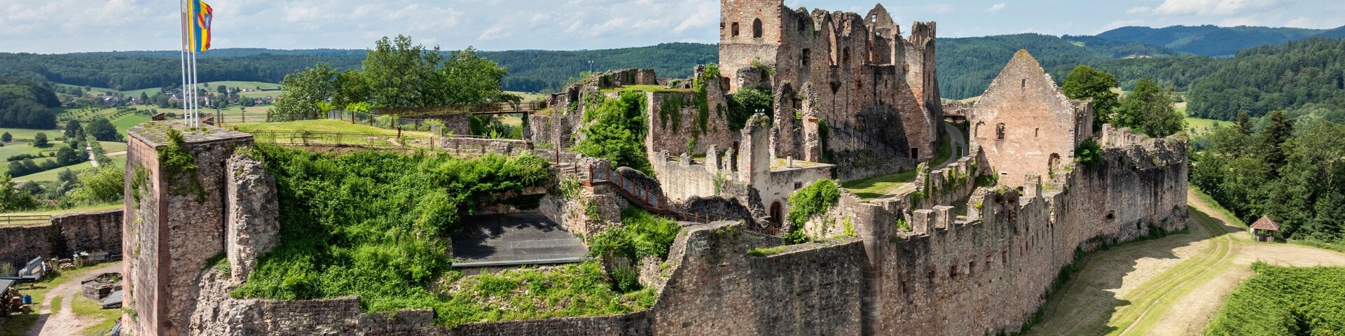 Um castelo histórico cercado por vegetação exuberante e um céu límpido.