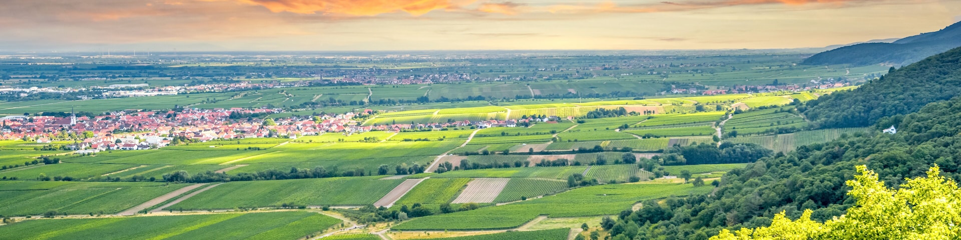 Paisagem rural com campos, uma aldeia e uma igreja.