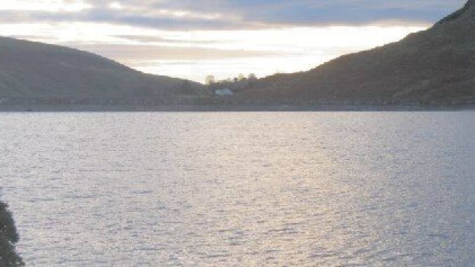 Upper Lliw reservoir wall. This is the view looking south down the east bank of the reservoir towards the dam wall at the south and the tower at the southwest end of the reservoir.