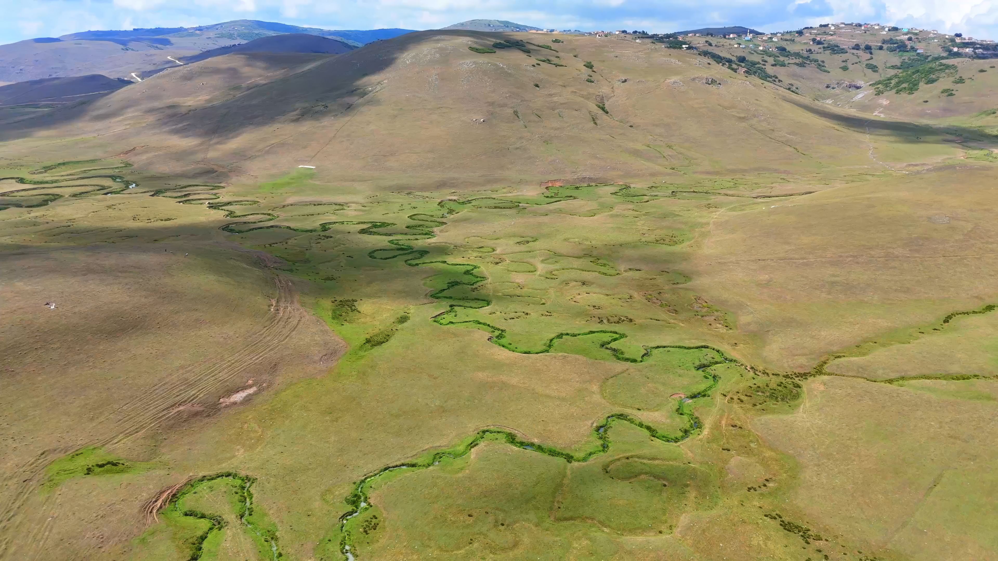 Paisagem montanhosa com riachos sinuosos e povoados dispersos.