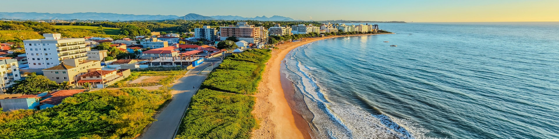 Uma cidade costeira com uma praia, um calçadão e edifícios ao longo da costa.