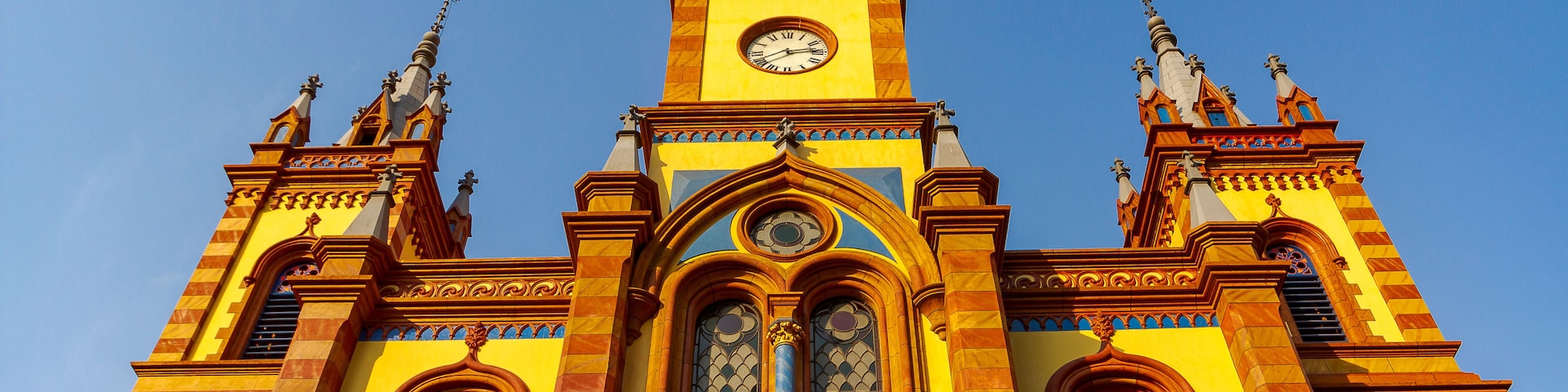 Uma igreja com uma torre do relógio, vitrais e detalhes arquitetônicos elaborados.
