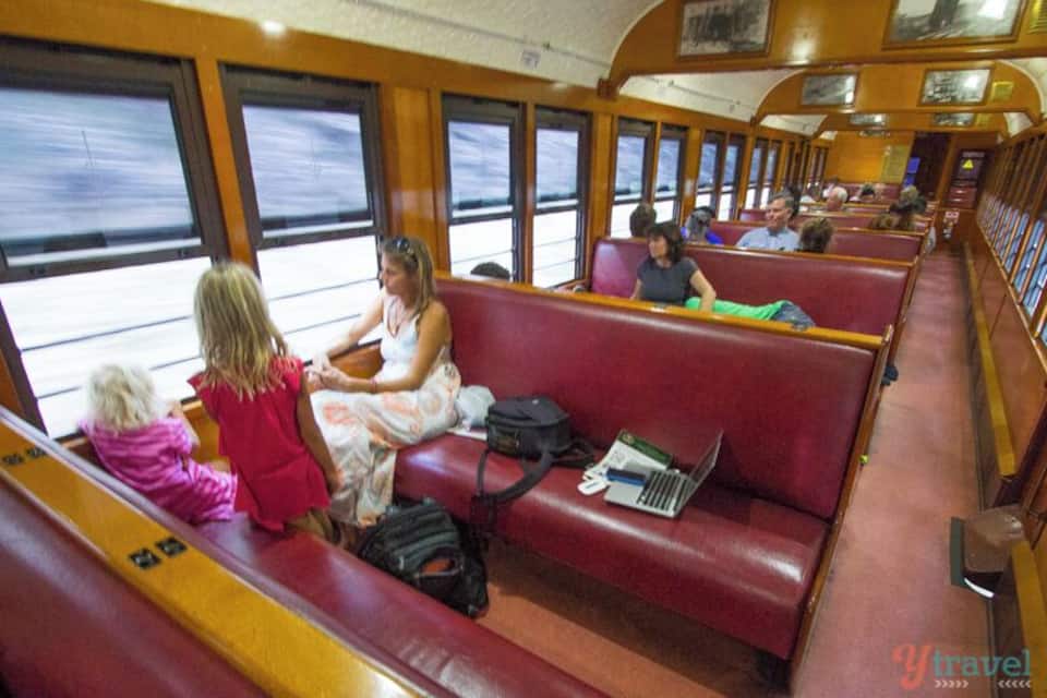 Um vagão de trem com assentos vermelhos e janelas.