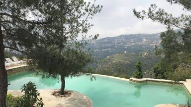 Piscina com vista para uma vila no topo de uma colina.
