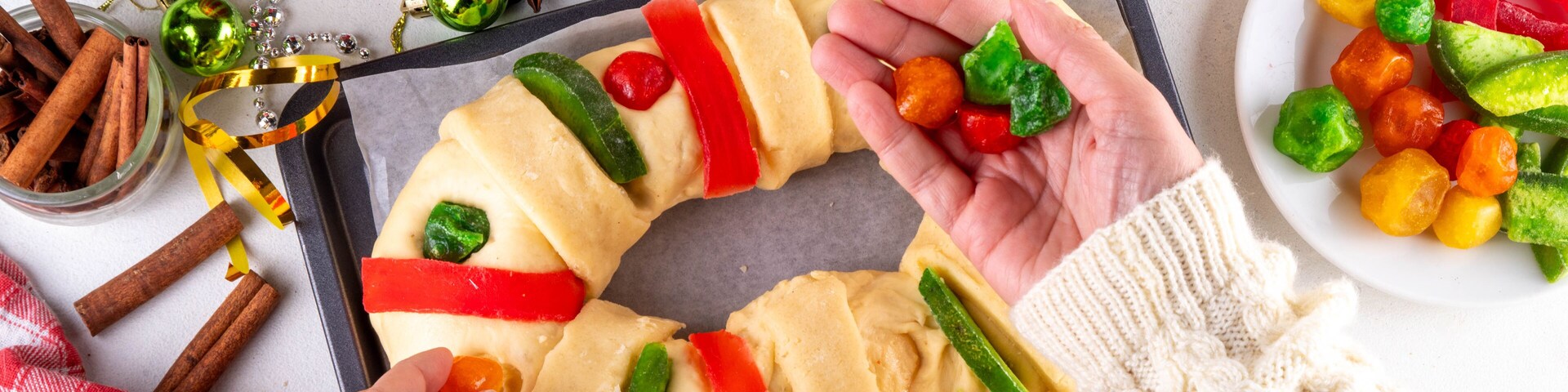 Uma pessoa prepara um pastel com pimentões verde e vermelho, rodeada de enfeites de Natal.