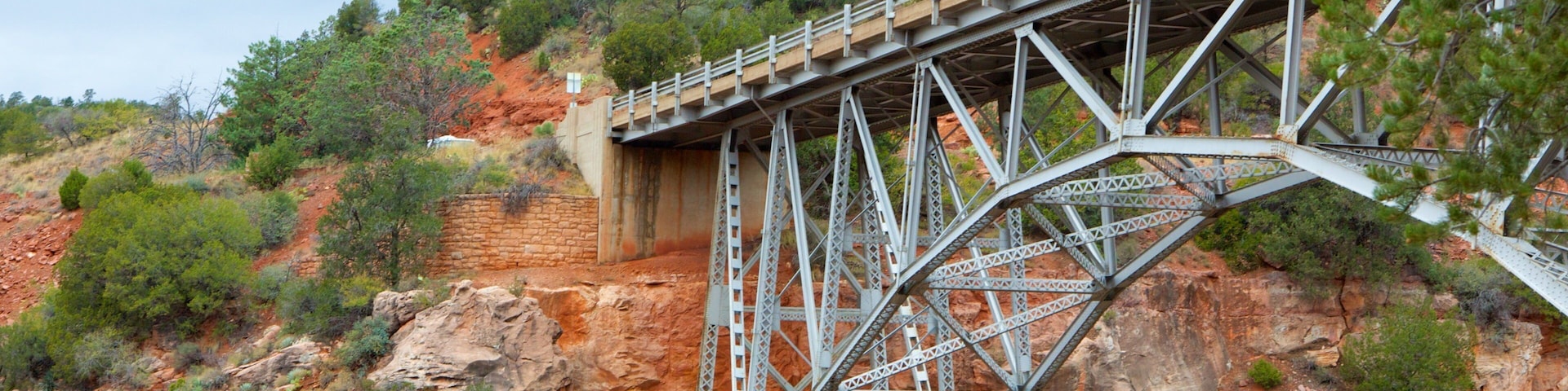 Uma ponte de aço sobre um penhasco rochoso com vegetação escassa.