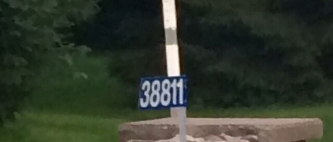 Placa indicadora para a Trilha de Caminhada Elgin, com base de pedra e placa azul.
