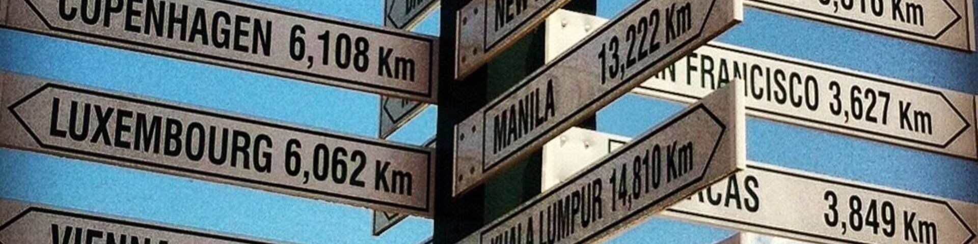 Conjunto de placas de sinalização indicando as distâncias para várias cidades.