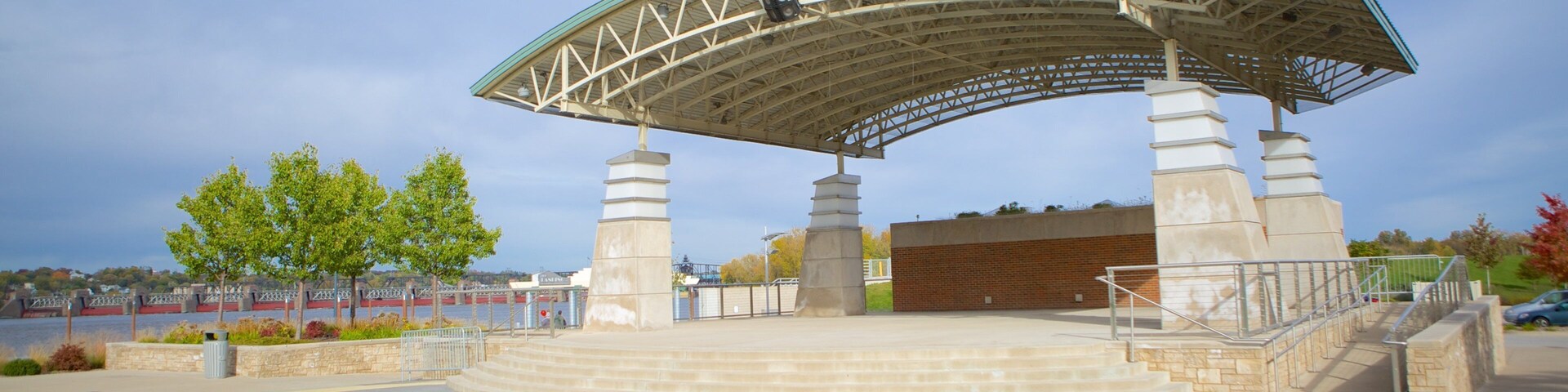 Um pavilhão coberto com um telhado curvo, uma parede de tijolos e um padrão circular no chão.