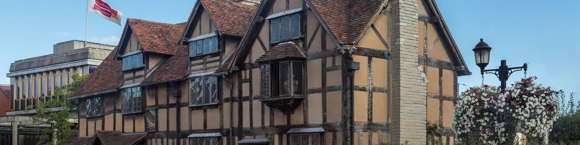 Um edifício em estilo Tudor com telhado de telhas vermelhas e janelas emolduradas a preto.