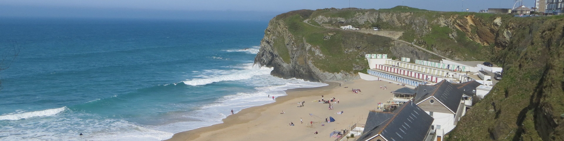 Uma cidade costeira com praia de areia, falésias e edifícios ao longo da orla.