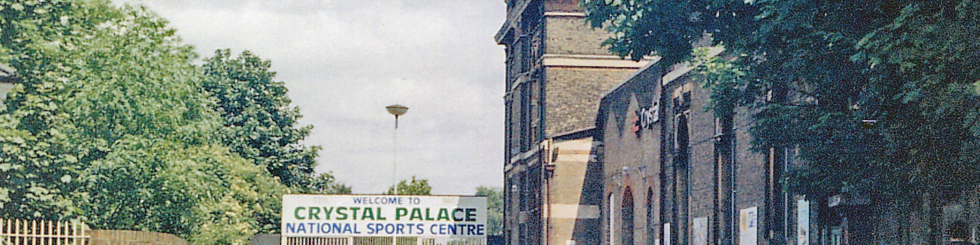 Entrance to Crystal Palace (Low Level) station, 1985. View NE off Anerley Hill: the ex-LB&SCR lines ran below, westward (in a tunnel) towards Balham, Clapham Junction and Victoria, eastward towards Norwood Junction etc. (See the various other images of this station). Clearly this is also the entrance to the celebrated Crystal Palace Sports Centre.