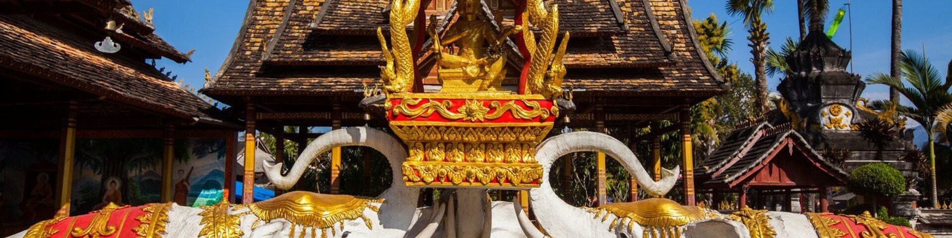 Um templo com telhado dourado e estátua de elefante branco.