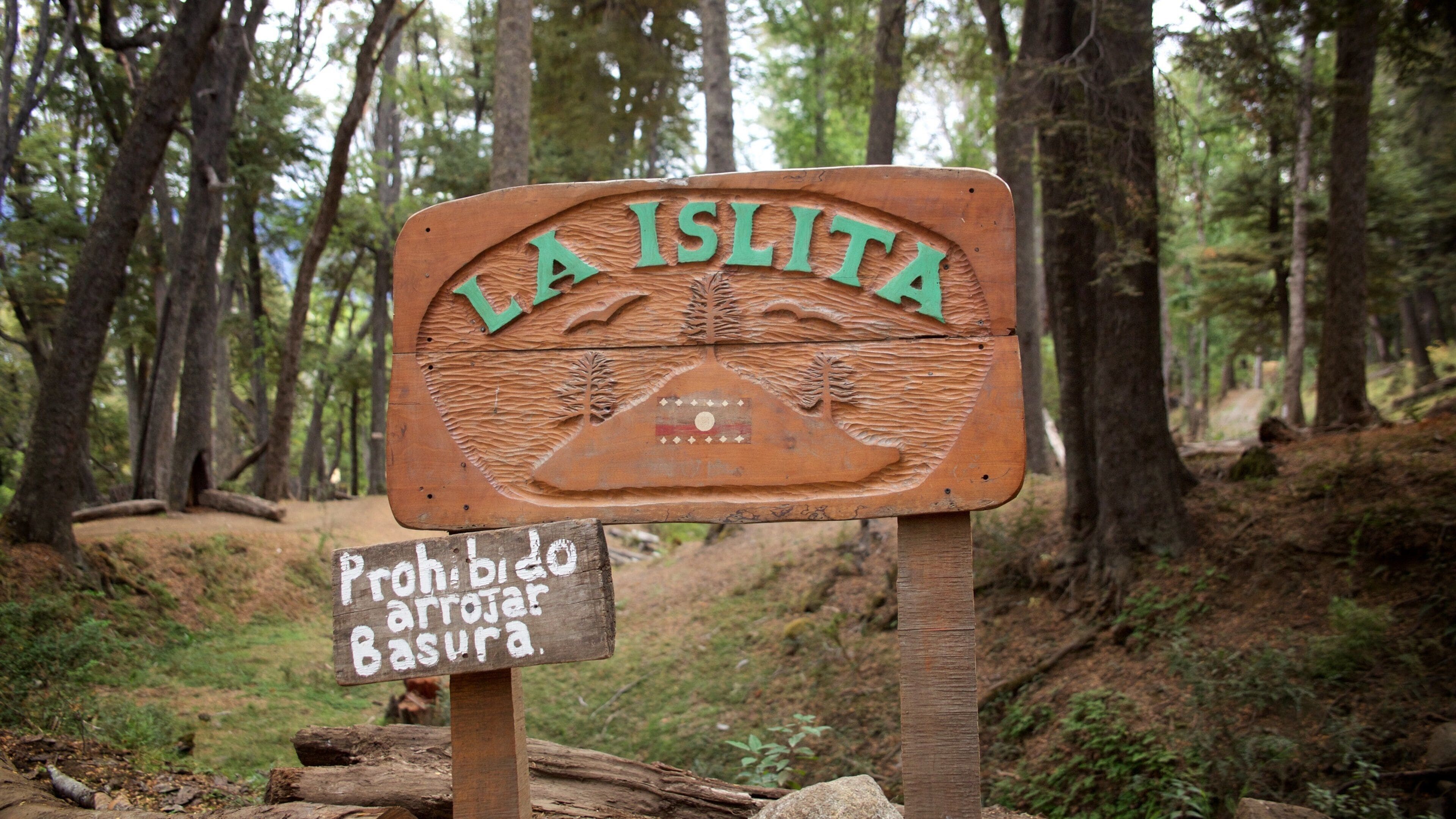 Uma placa de madeira com 'LA ISLITA' e um sinal de proibição de 'arrojar lixo'.