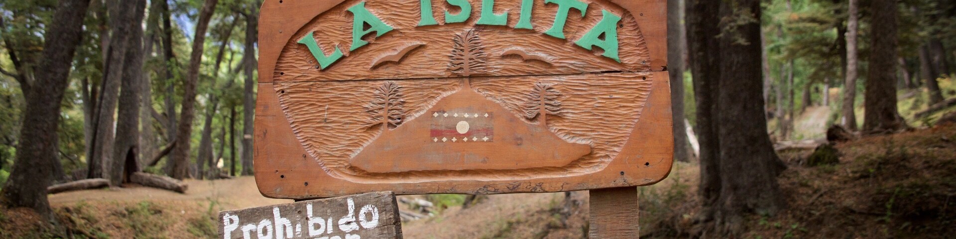 Uma placa de madeira com 'LA ISLITA' e um sinal de proibição de 'arrojar lixo'.