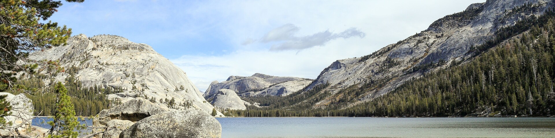 Um lago de montanha com águas cristalinas, cercado por terreno rochoso e árvores.