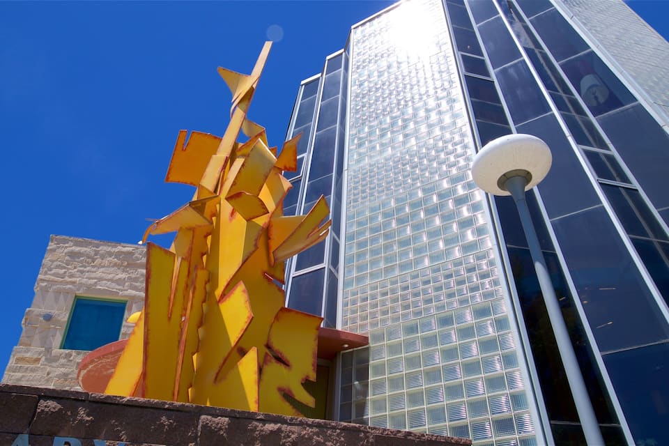 Um edifício moderno com fachada de vidro e uma grande escultura amarela na frente.