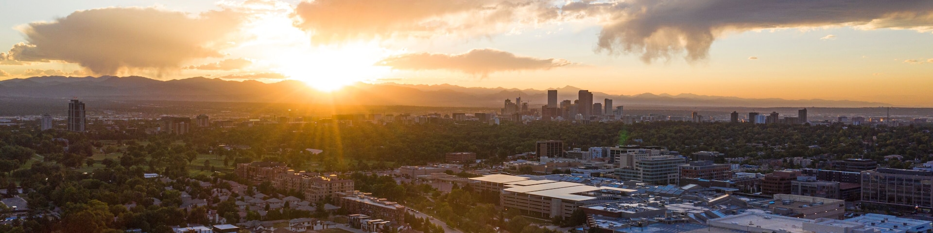 Paisagem urbana ao pôr do sol, com um edifício imponente e uma estrada sinuosa.